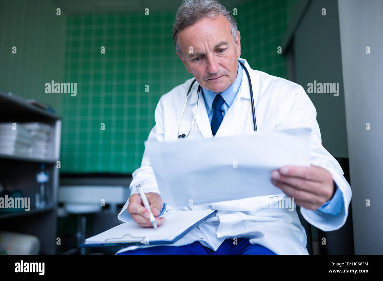 Doctor checking medical report Stock Photo - Alamy
