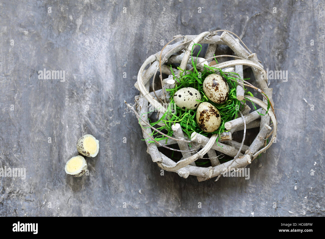 Wicker nest of twigs and quail eggs on a gray background, symbol of ...
