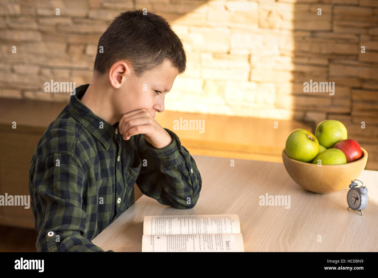Young Boy Thinking Over a Book on Desk at Home Stock Photo - Alamy