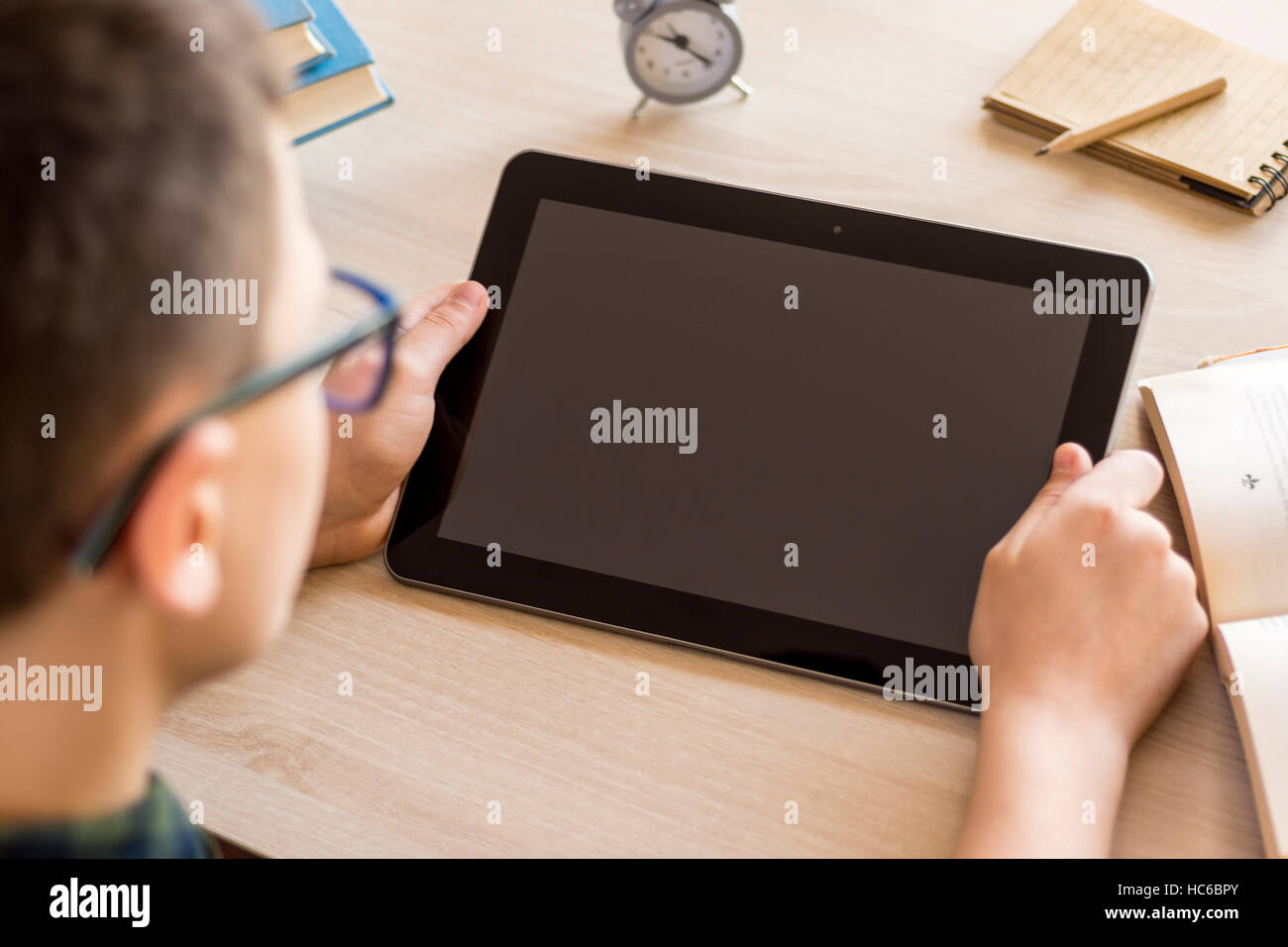 Boy Using Digital Tablet while Sitting on Desk at Home. Reading and ...