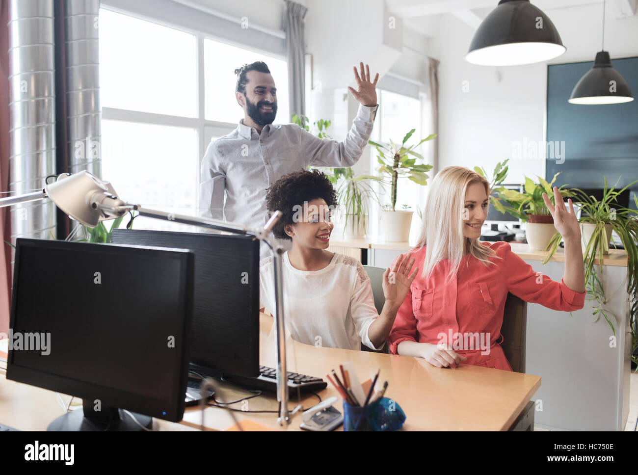happy creative team waving hands in office Stock Photo - Alamy