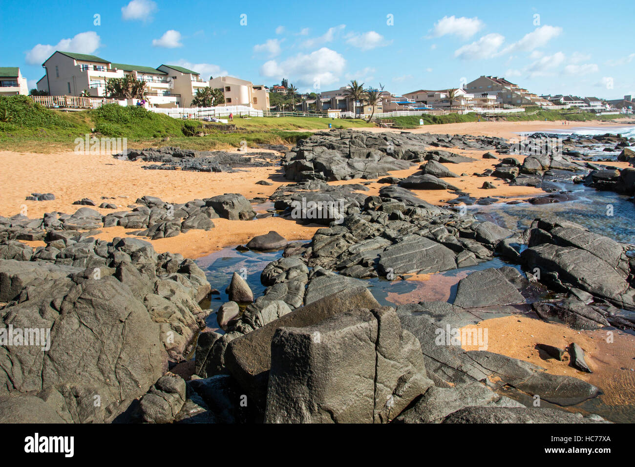 Beach sand rocks against blue sky city skyline in Ballito South Africa ...