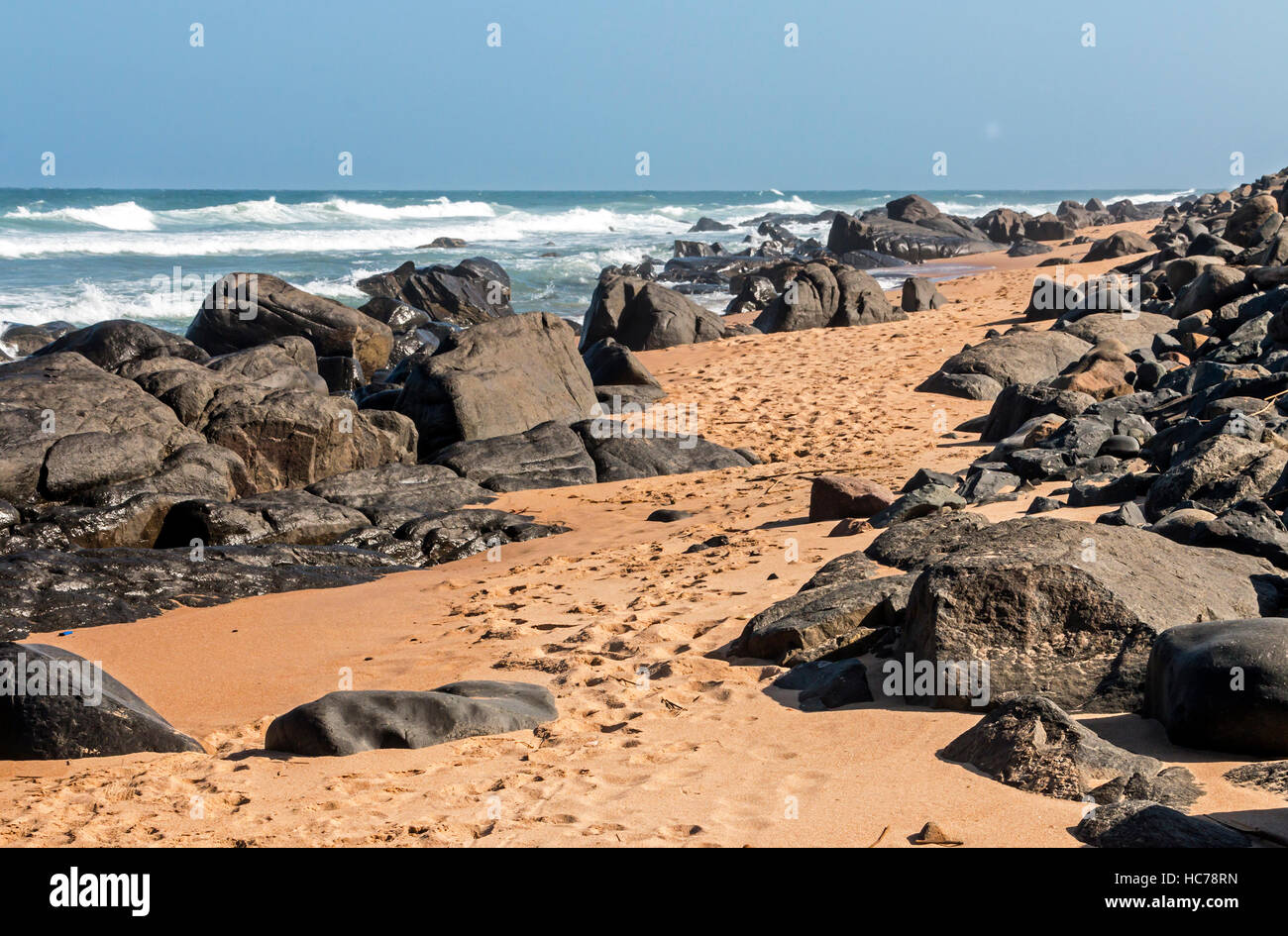 Beach sand rocks ocean and waves against blue skyline in South Africa ...