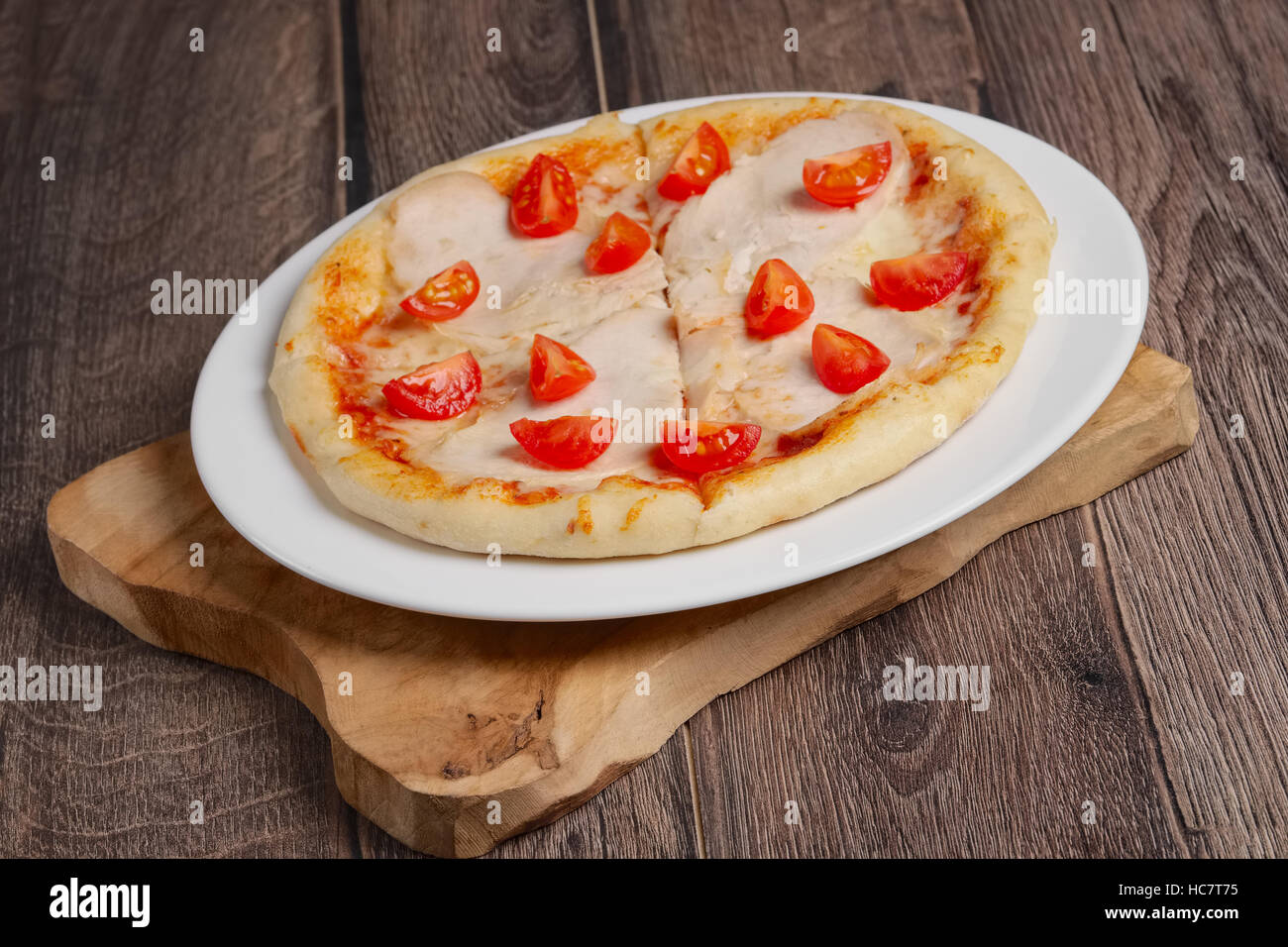 pizza with ham and tomato on wooden plate Stock Photo - Alamy