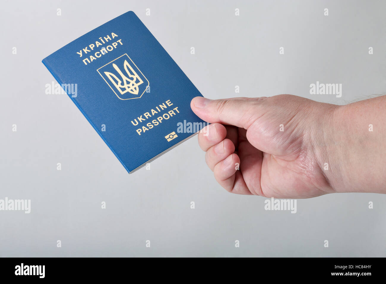 Hand Holding Ukrainian Biometric Passport Against White Background
