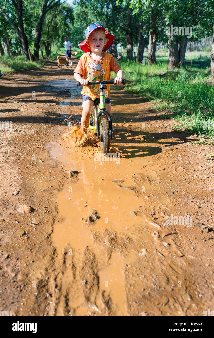 A young boy on a bicycle about to ride through a muddy puddle Stock ...