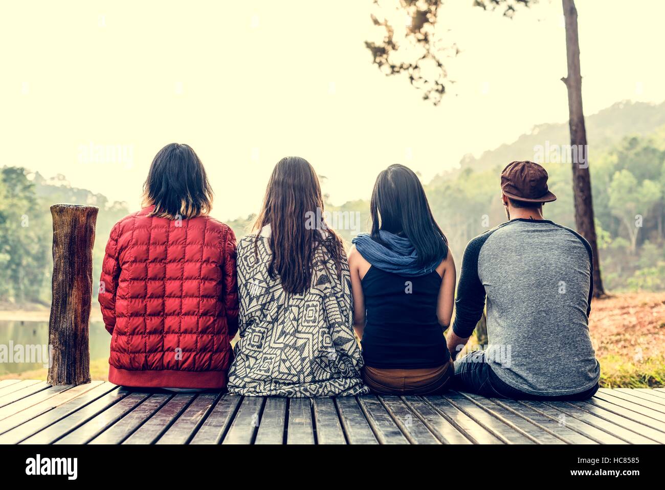 Friends Sitting in a Row Outdoors Concept Stock Photo - Alamy