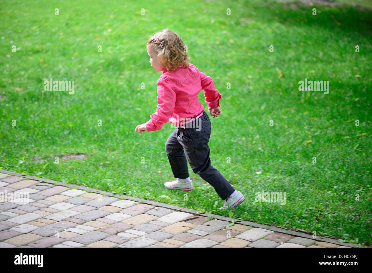 Funny little girl runing on green grass in park Stock Photo - Alamy