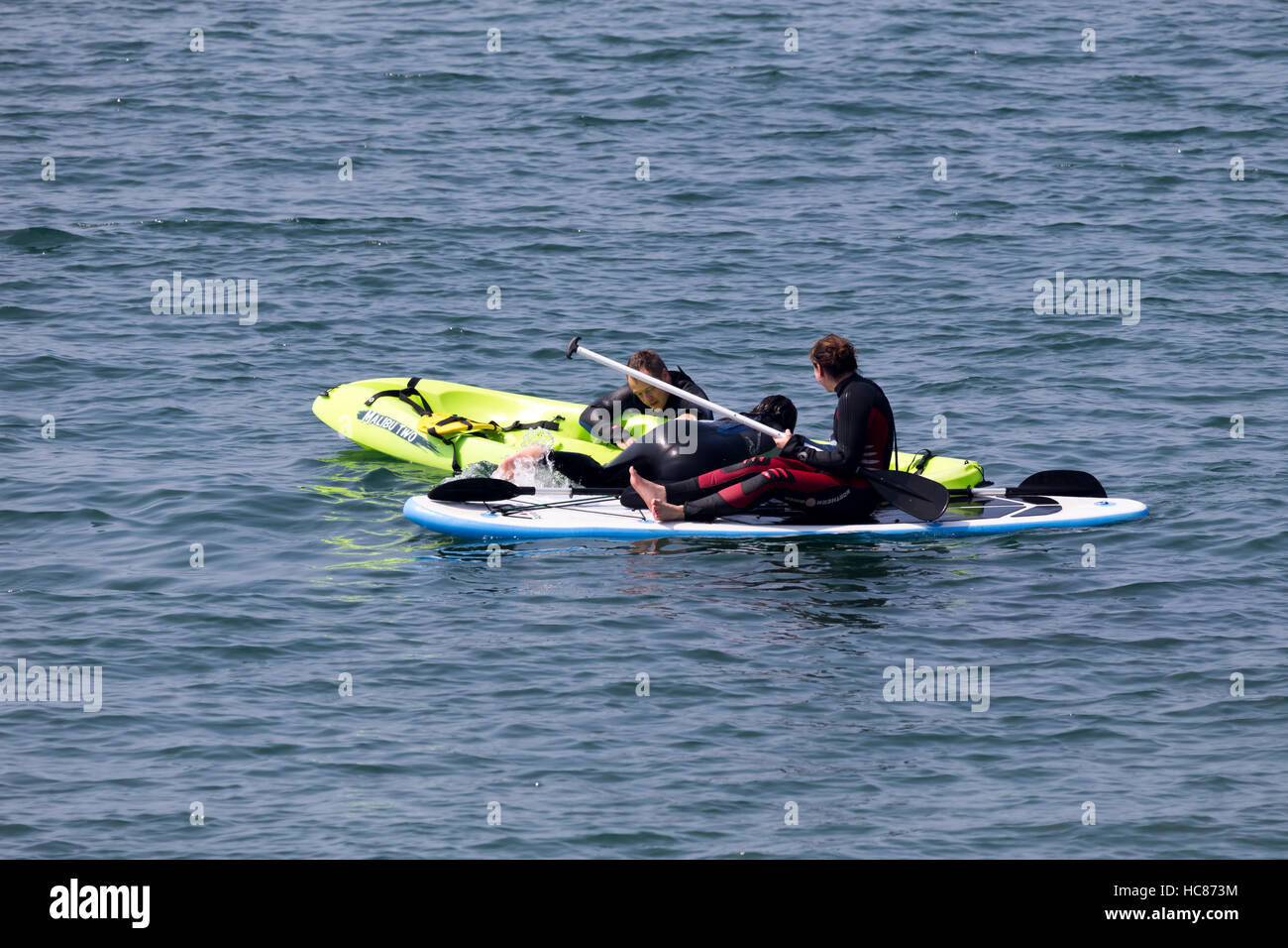 Two people who have fallen out of a kayak at sea Stock Photo - Alamy