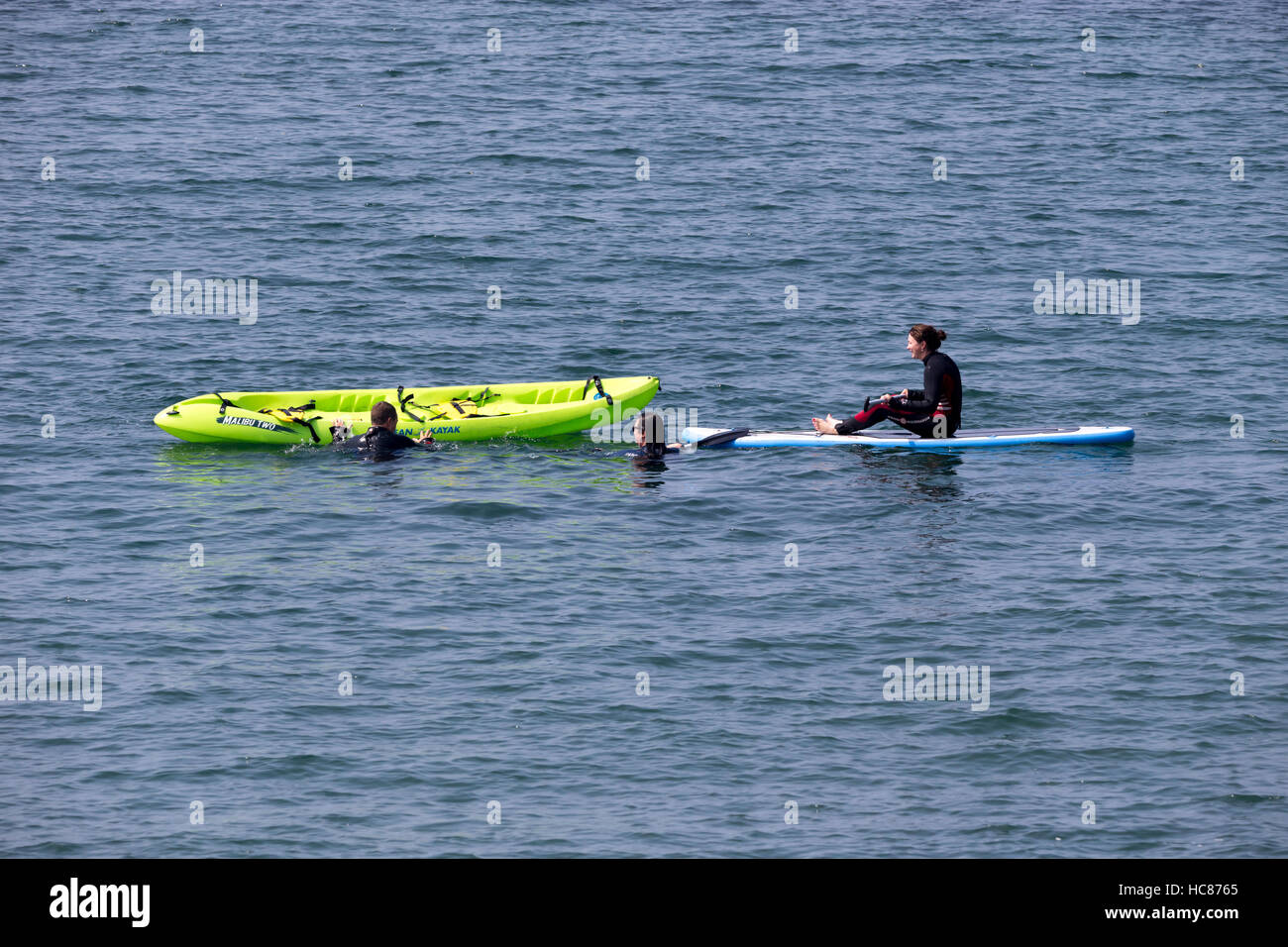 Two people who have fallen out of a kayak at sea Stock Photo - Alamy