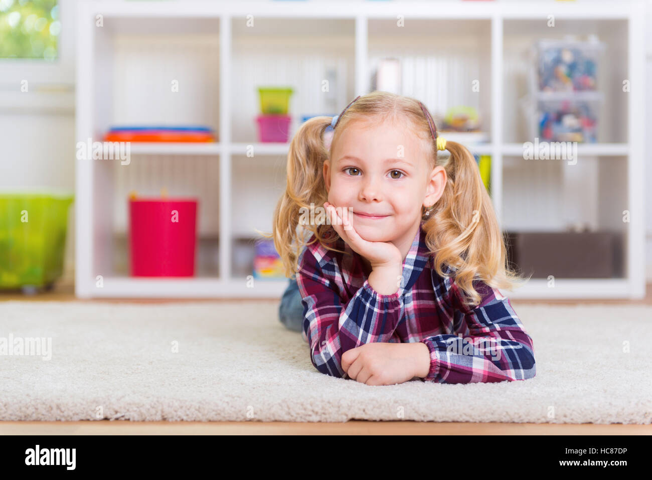 Cute little girl lay on carpet at home Stock Photo - Alamy