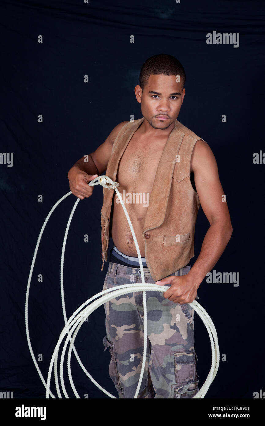 Handsome black man in a leather vest and working with a lasso Stock ...