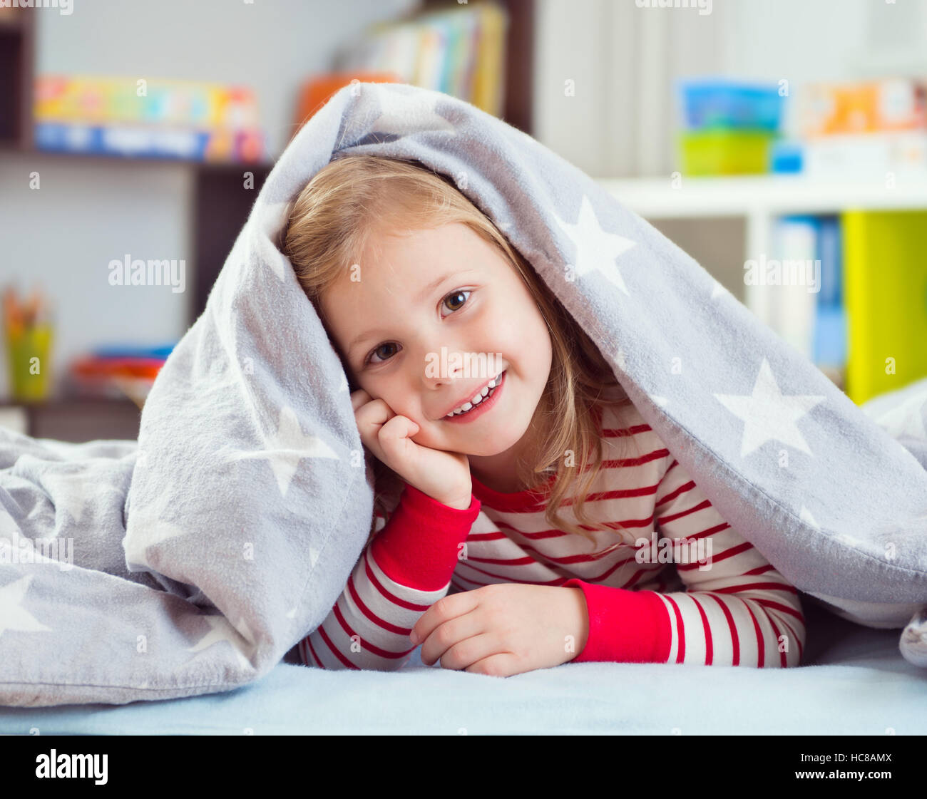 Pretty little girl in sleepwear lying under blanket Stock Photo - Alamy