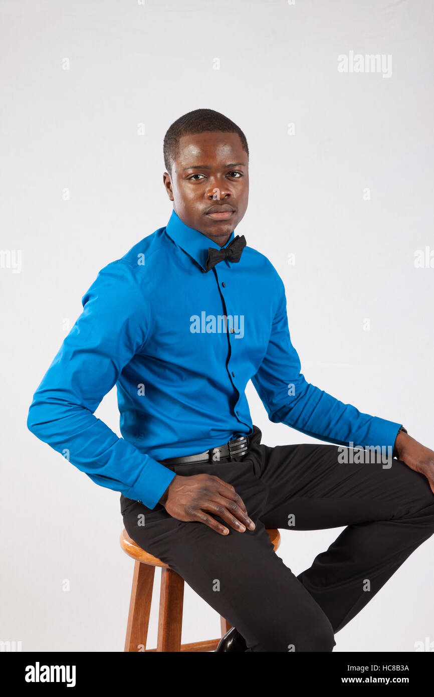 Handsome black man sitting on a stool and looking thoughtfully at the ...