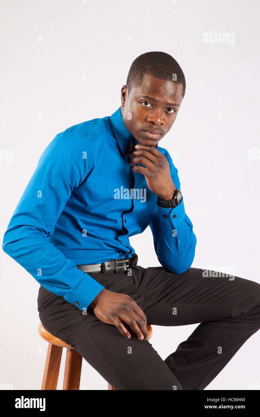 Handsome black man sitting on a stool and looking thoughtfully at the ...
