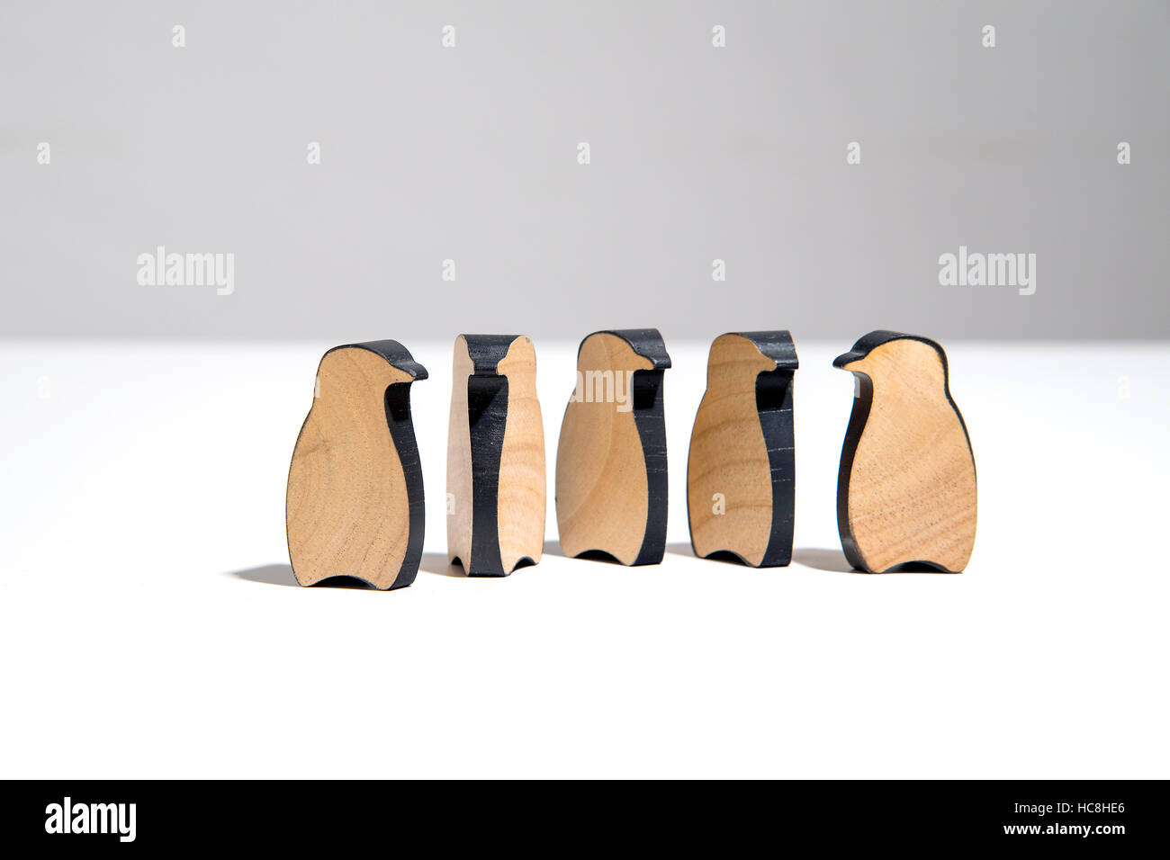 Vintage wooden penguin figures huddled together on a white winter ...