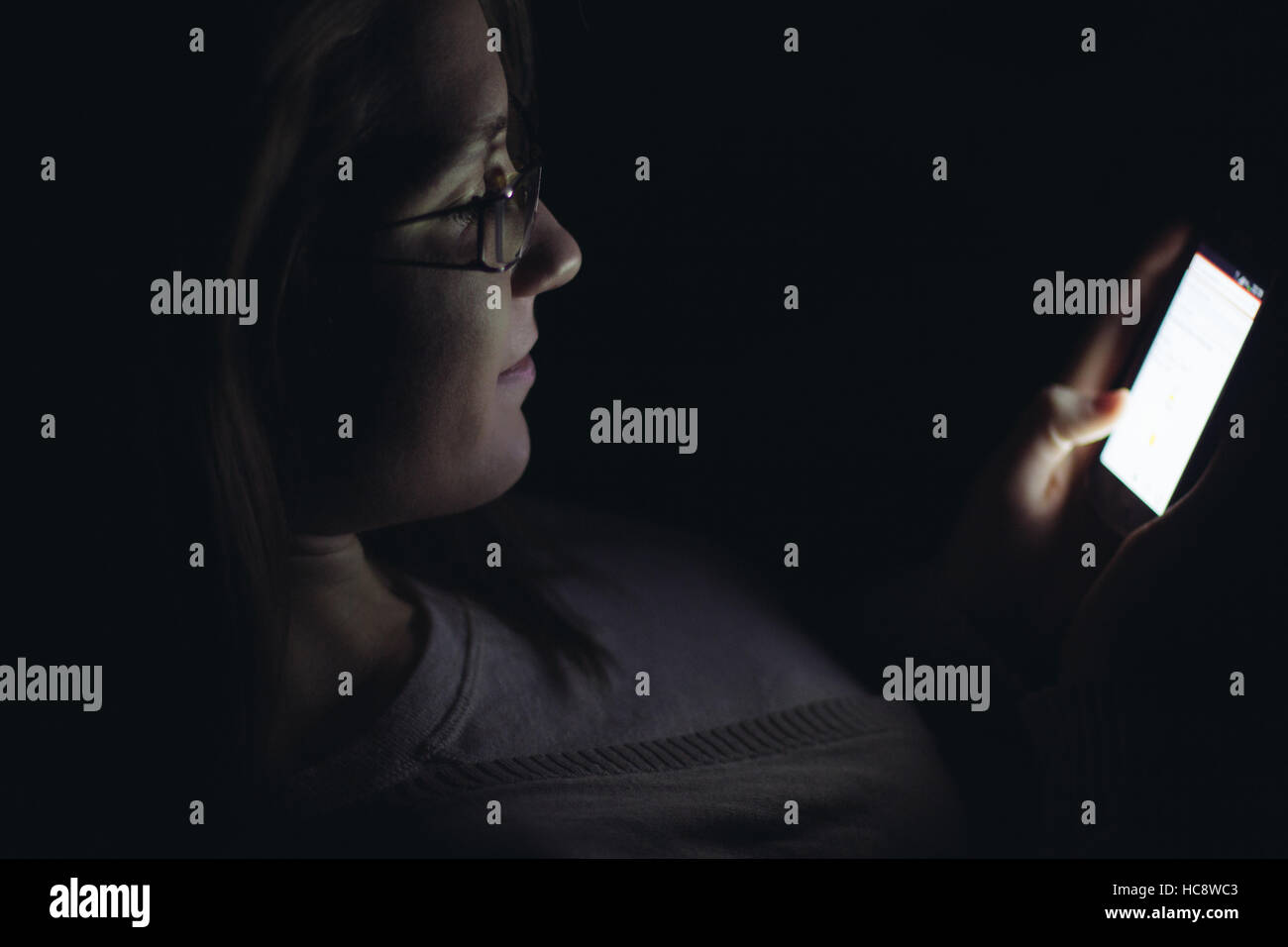 Young woman using mobile phone in dark room at home Stock Photo - Alamy