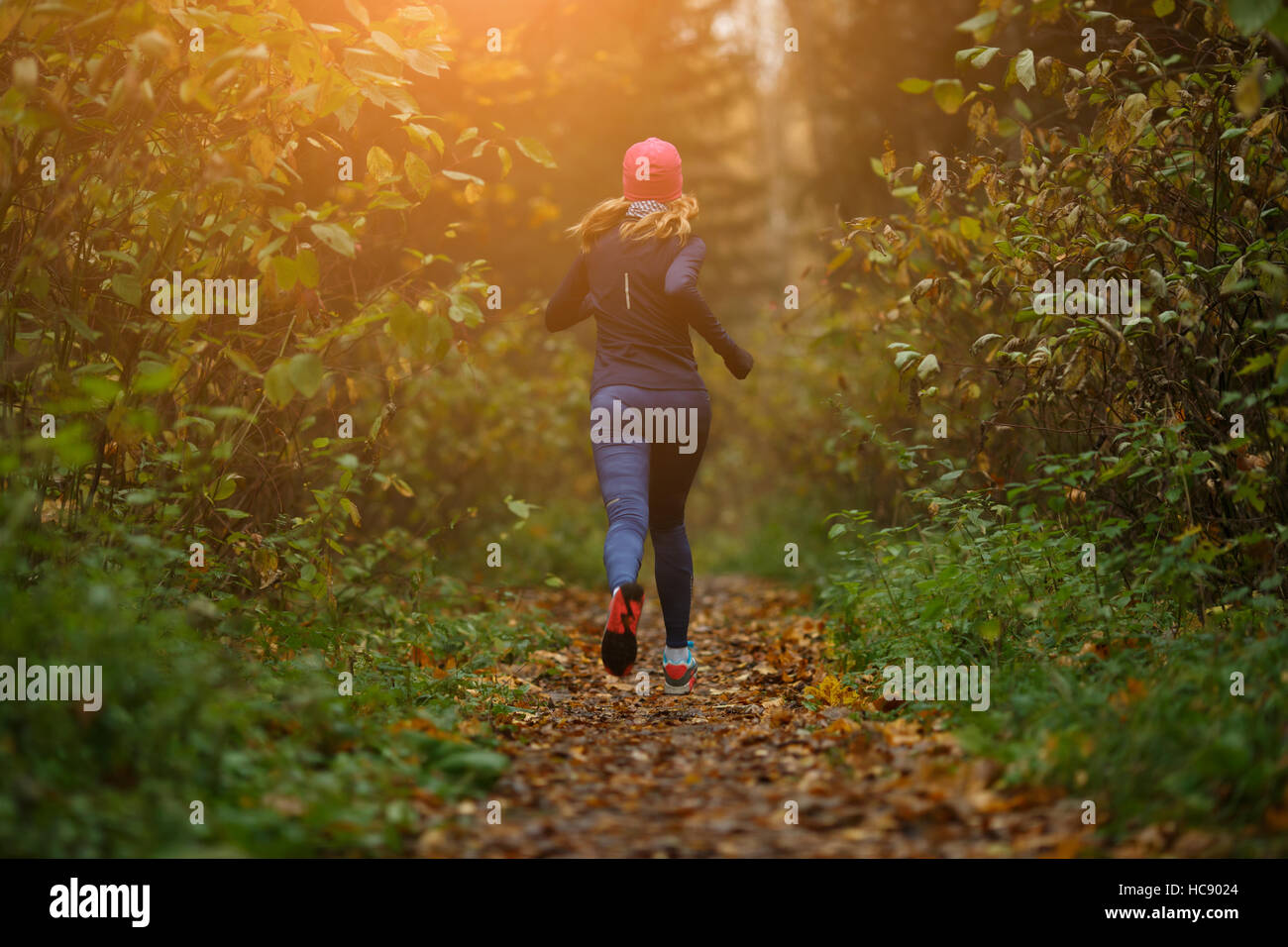 Blonde woman running among trees Stock Photo - Alamy