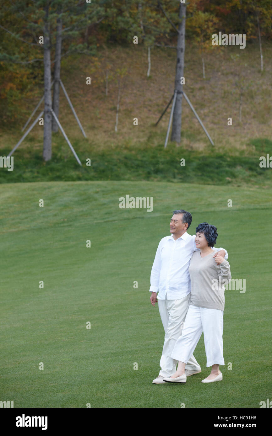 Side view of loving senior couple walking together in field Stock Photo ...