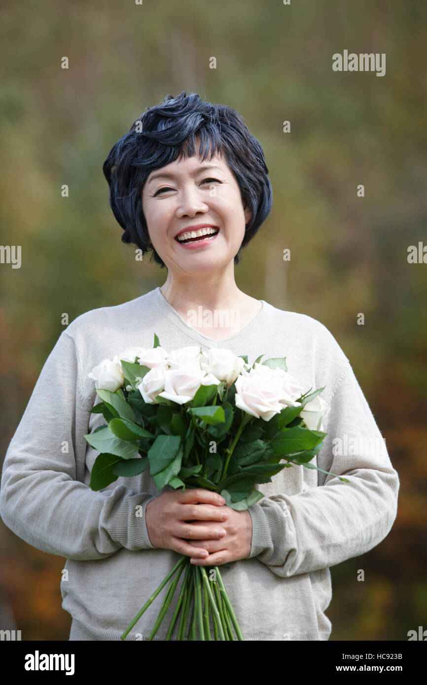 Smiling old woman holding roses outdoors Stock Photo - Alamy