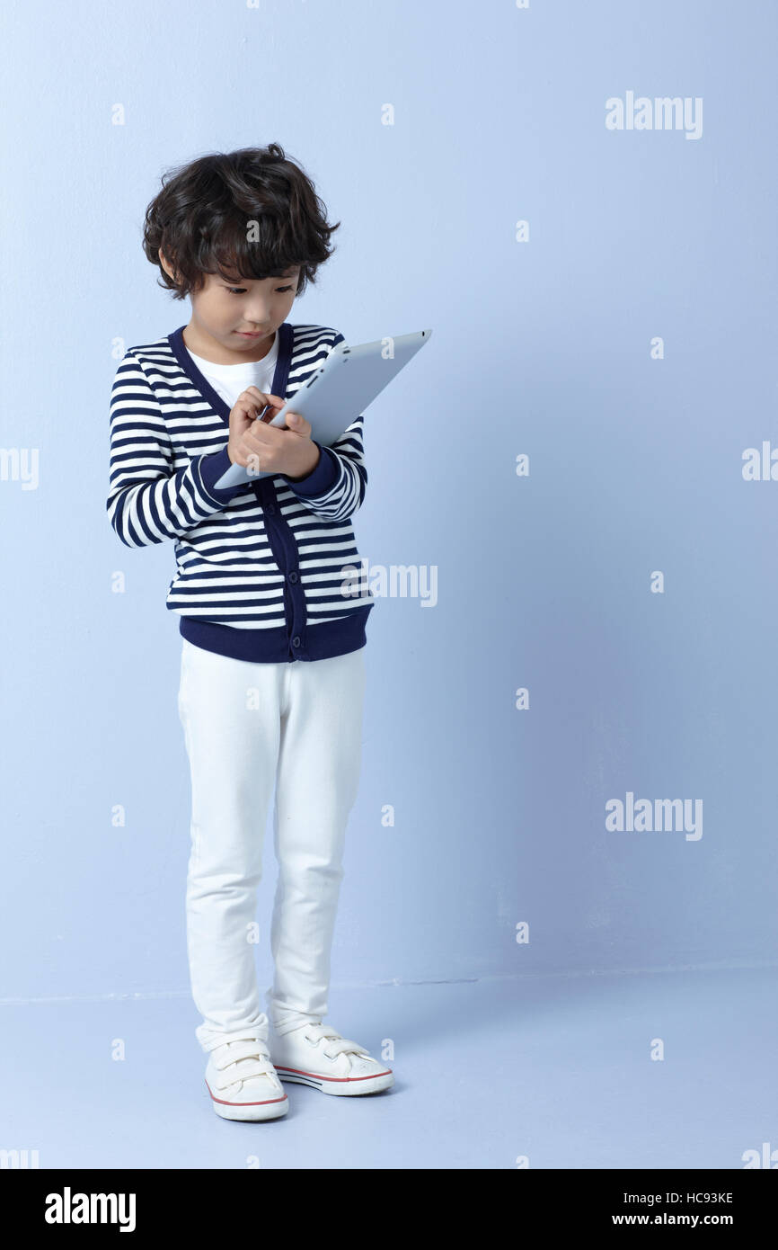 Smiling boy with tablet standing looking down Stock Photo - Alamy