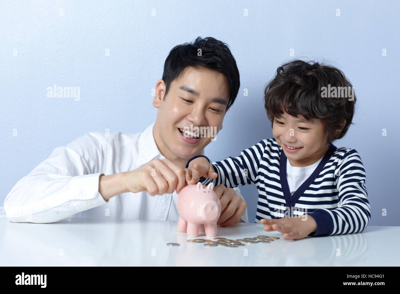 Portrait of smiling father and son putting coins into piggy bank Stock ...