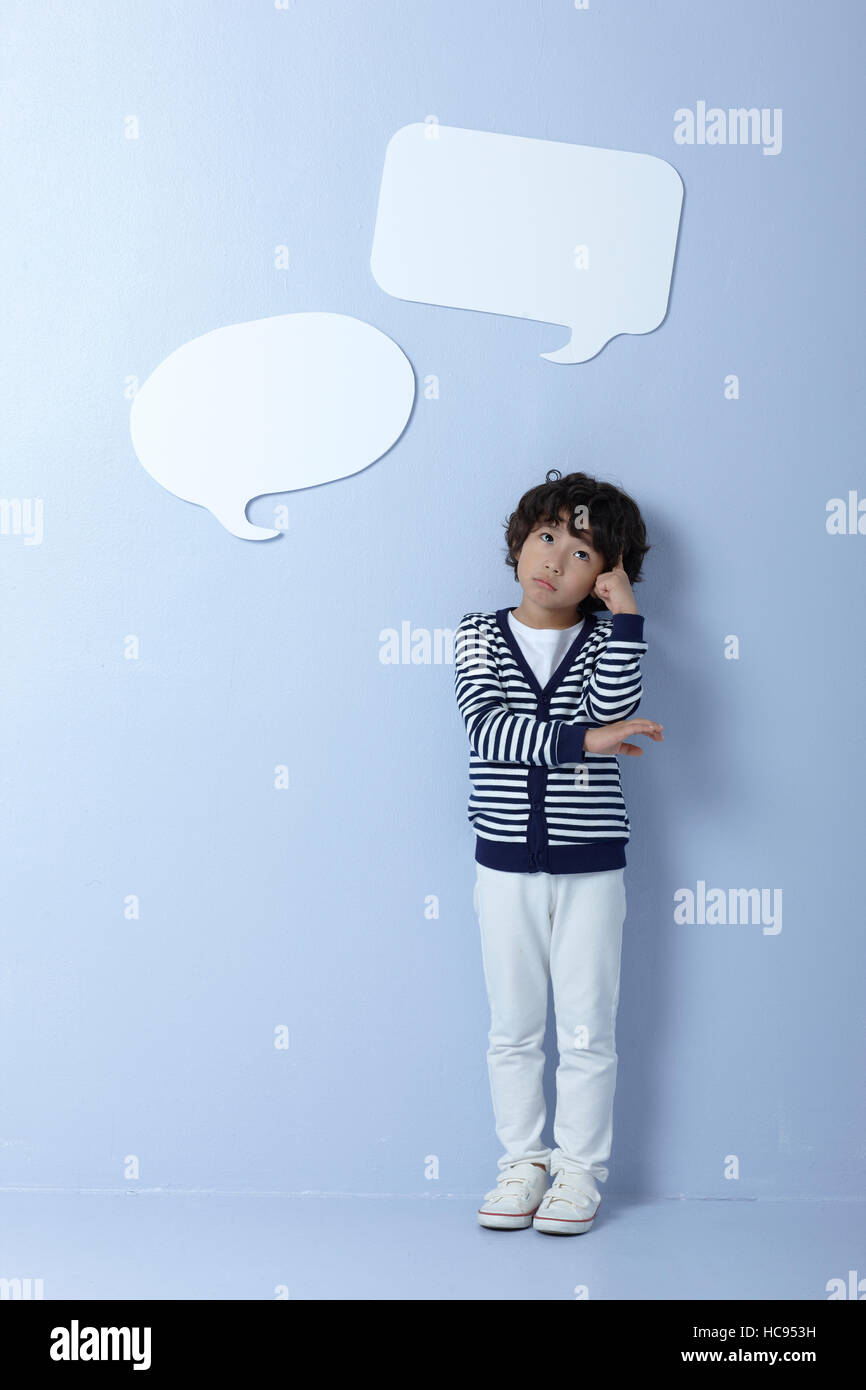 Boy standing thinking with speech balloons Stock Photo - Alamy