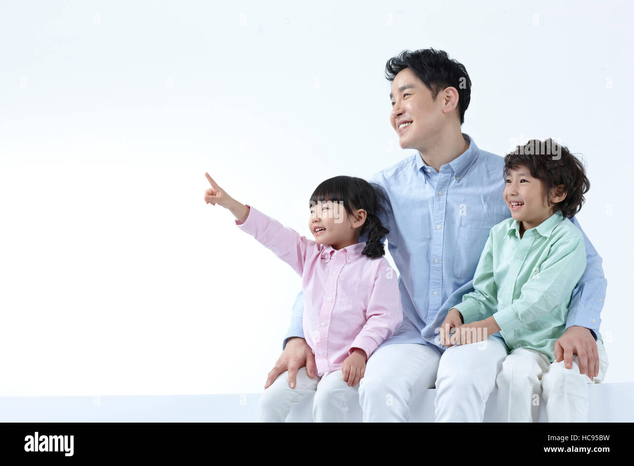 Smiling boy and girl sitting with their father looking up Stock Photo - Alamy
