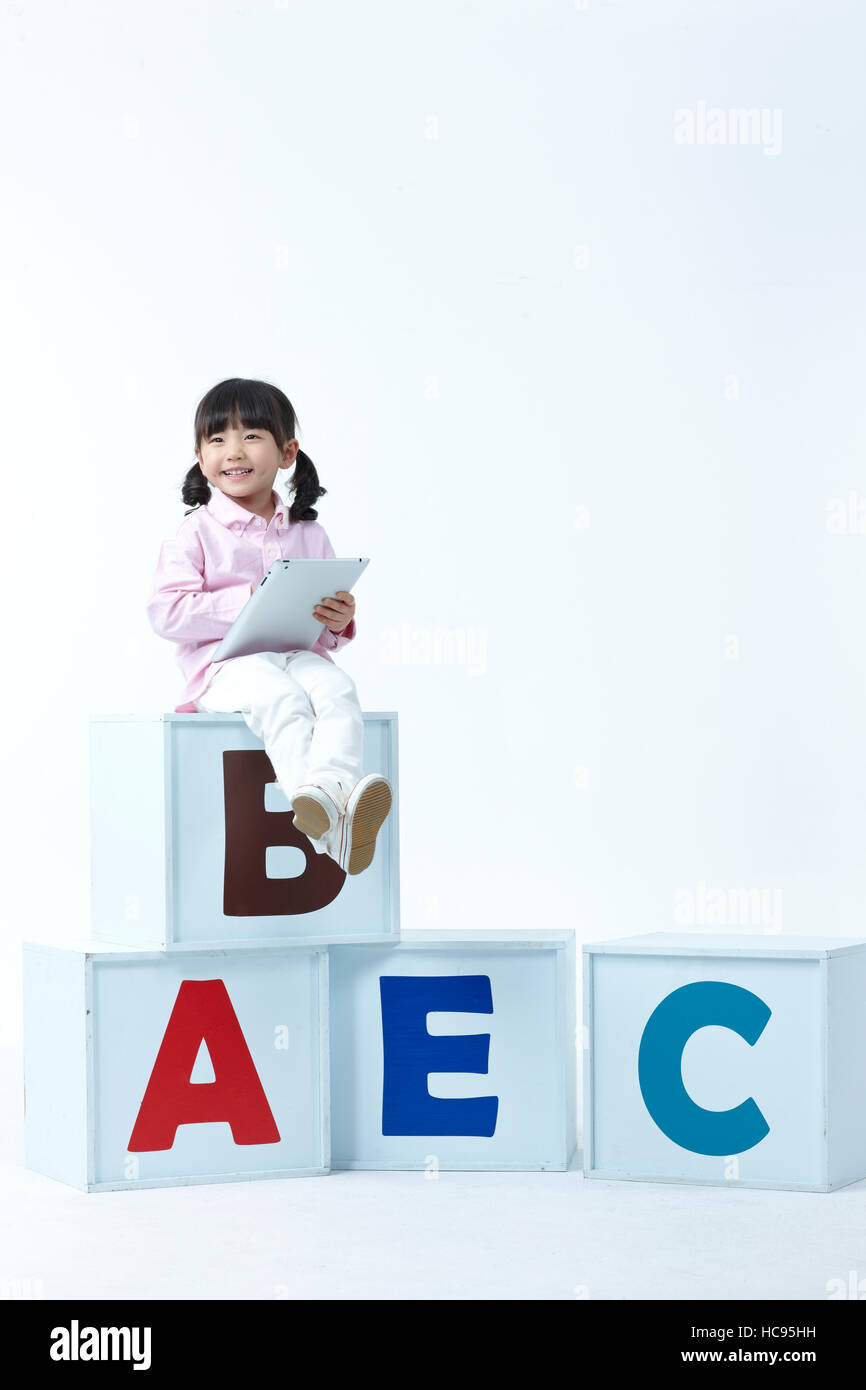Smiling girl sitting on alphabet blocks Stock Photo - Alamy