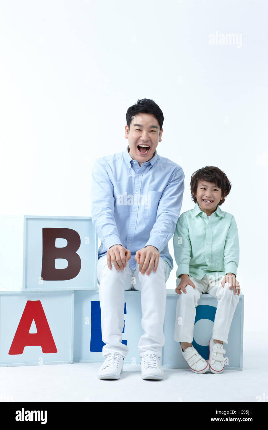 Smiling father and boy sitting on alphabet blocks Stock Photo - Alamy