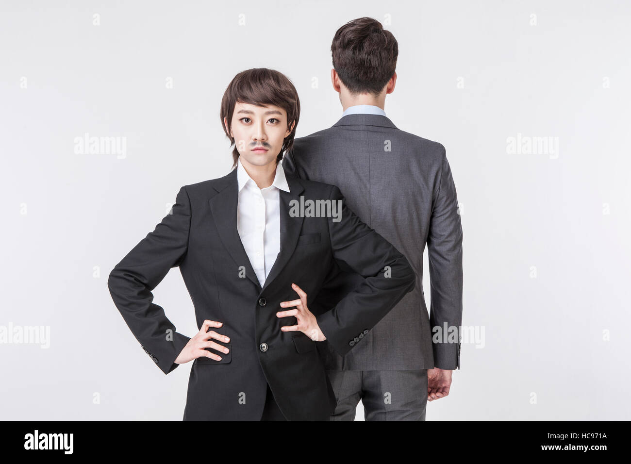 Woman disguising herself as a businessman standing back to back with a ...