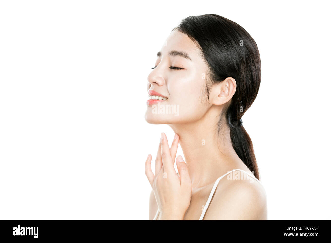 Side view portrait of young smiling woman touching her neck closing ...