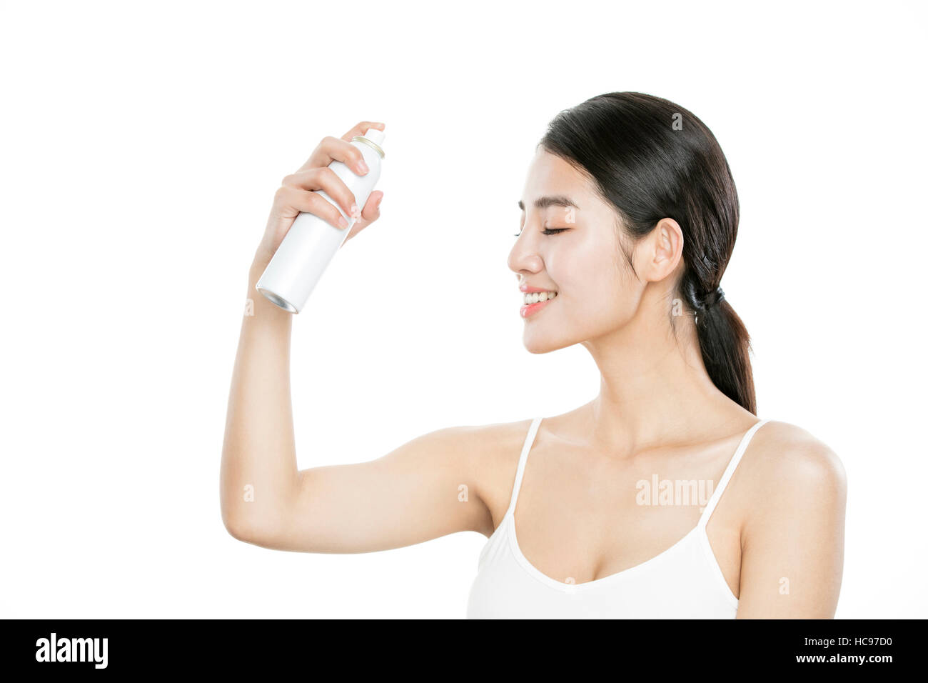 Side view portrait of young smiling woman spraying mist on her face ...