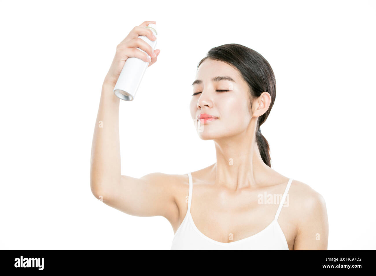 Side view portrait of young smiling woman spraying mist on her face ...