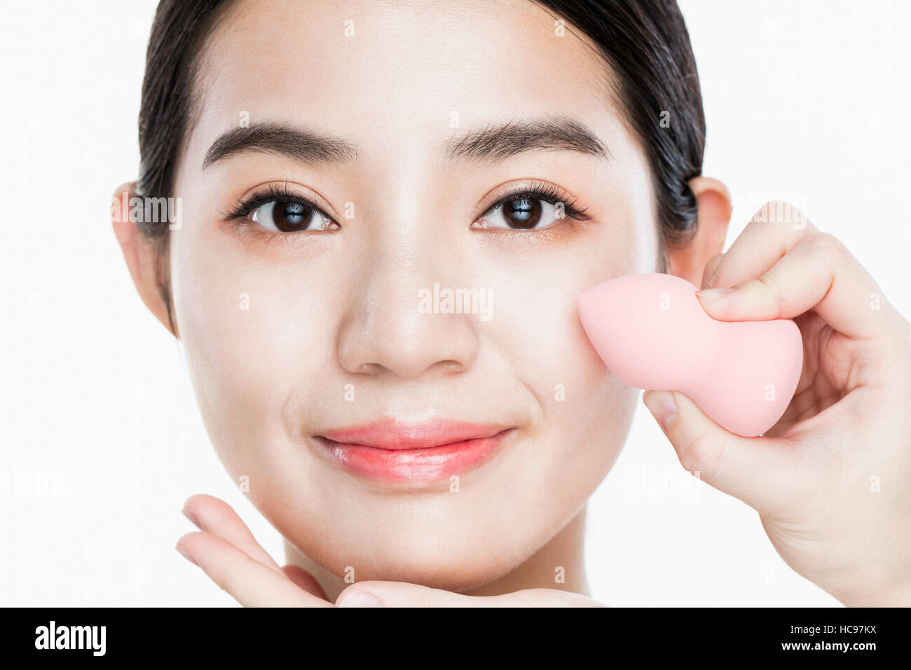 Face of young smiling woman using make up sponge Stock Photo - Alamy