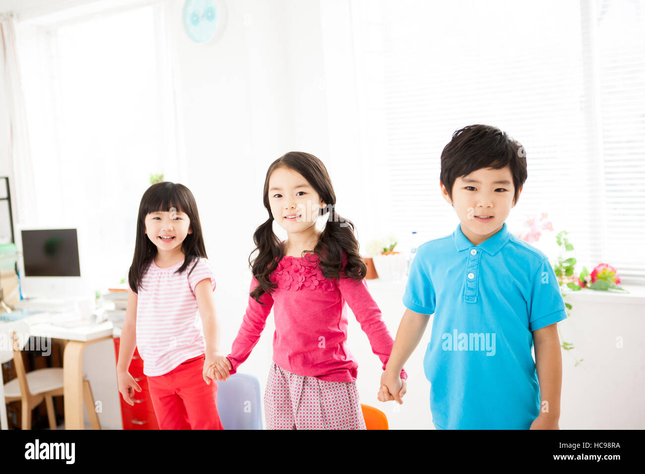 Smiling children hand in hand indoors Stock Photo - Alamy