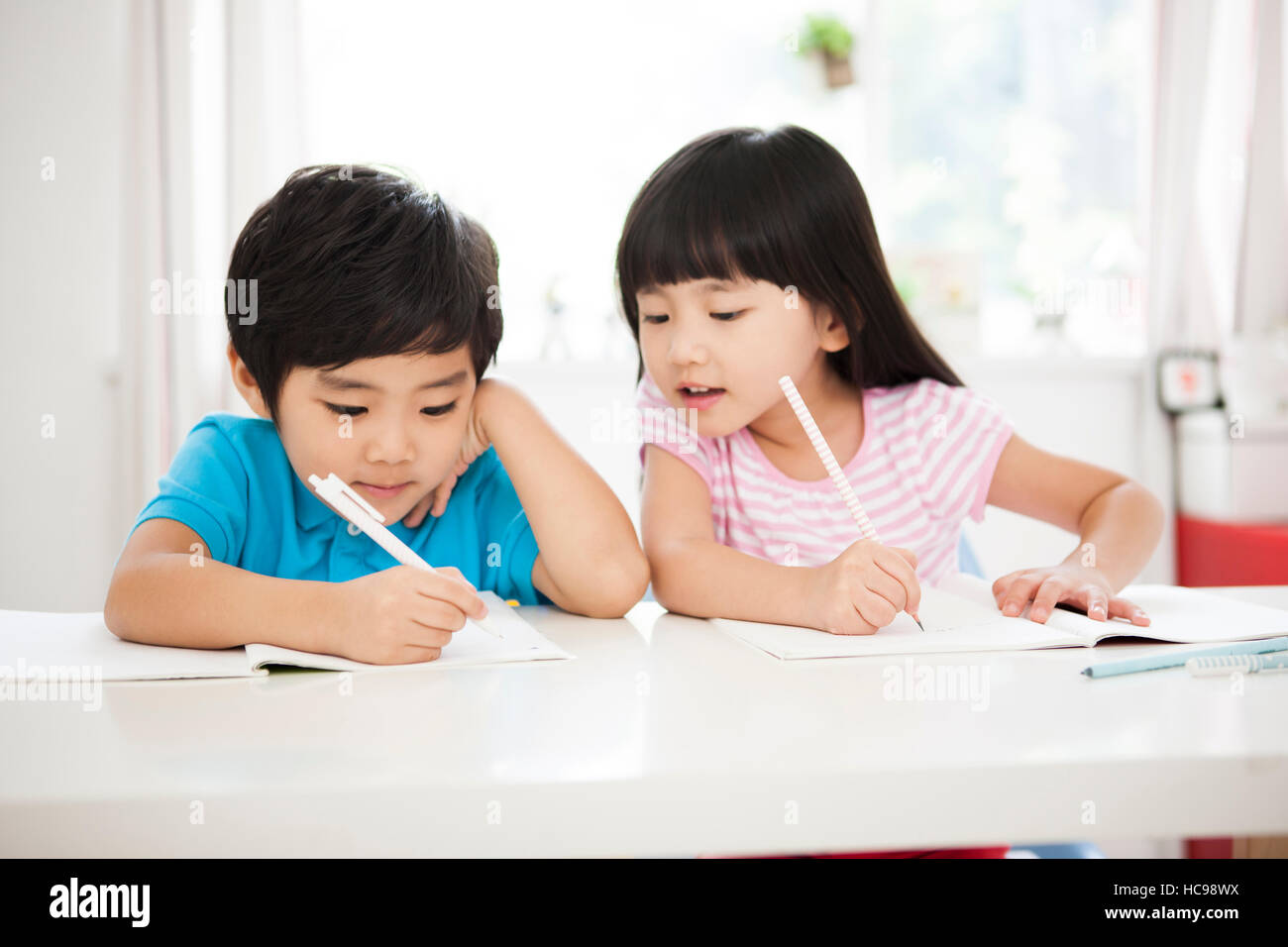 Portrait of smiling boy and girl holding pencils and writing Stock ...