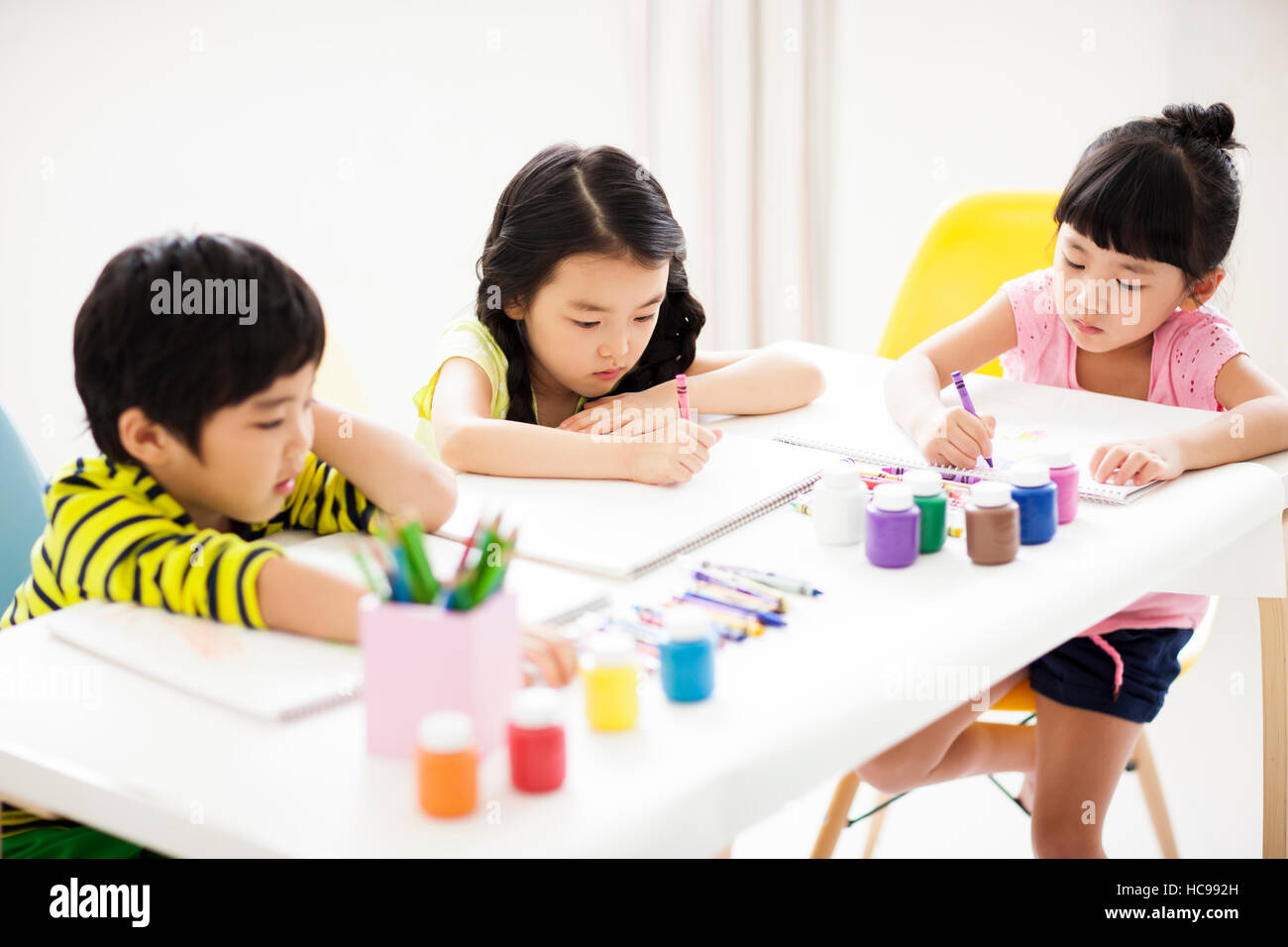 Three children drawing pictures Stock Photo - Alamy