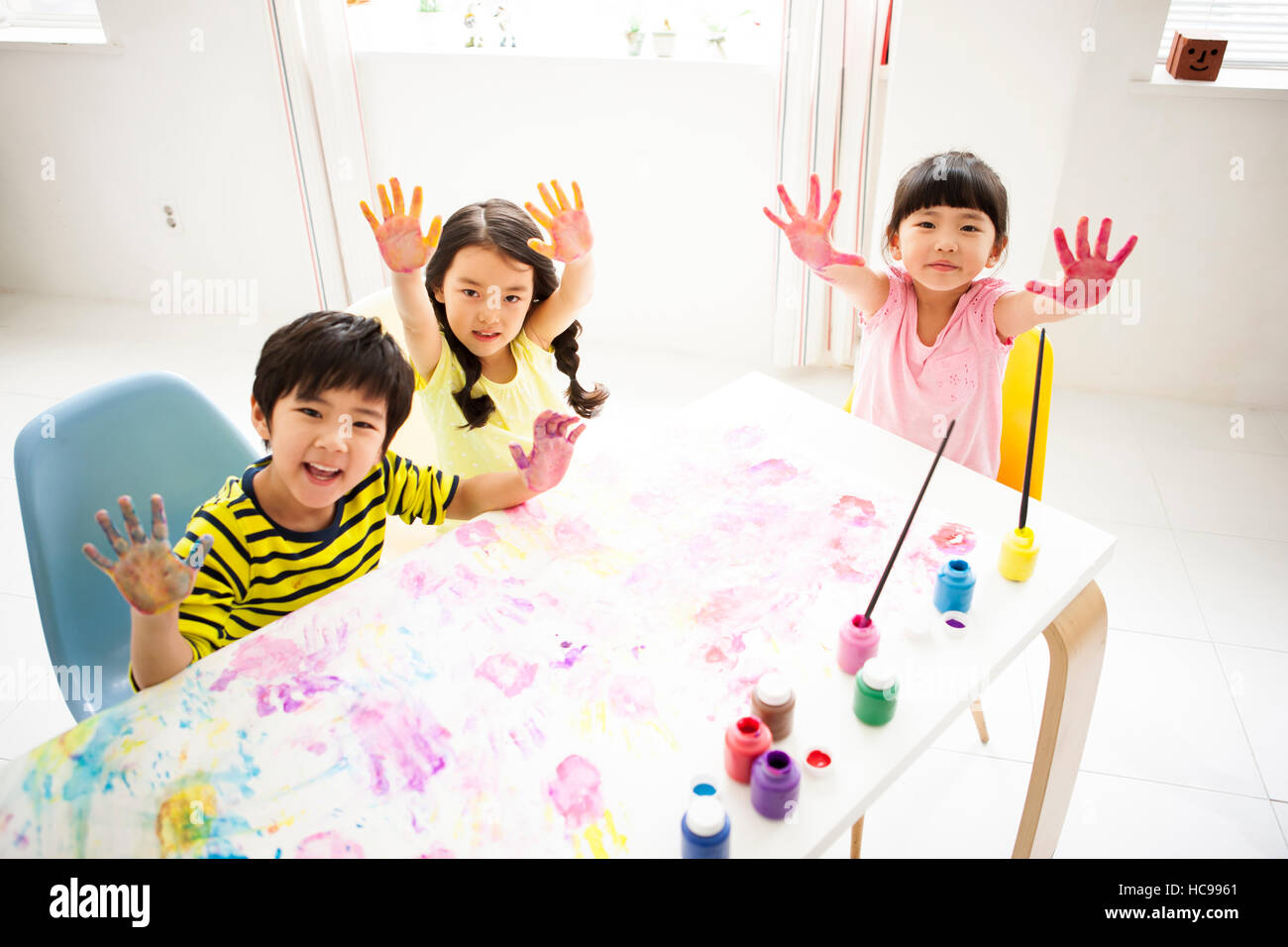 Three smiling children enjoying hand printing Stock Photo - Alamy