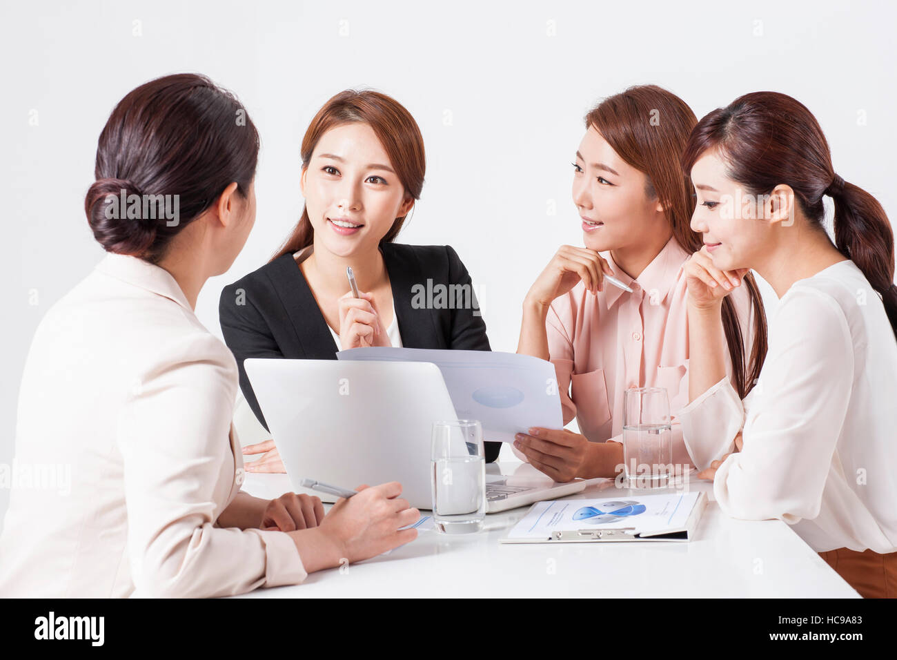 Four young smiling businesswomen having a meeting Stock Photo - Alamy