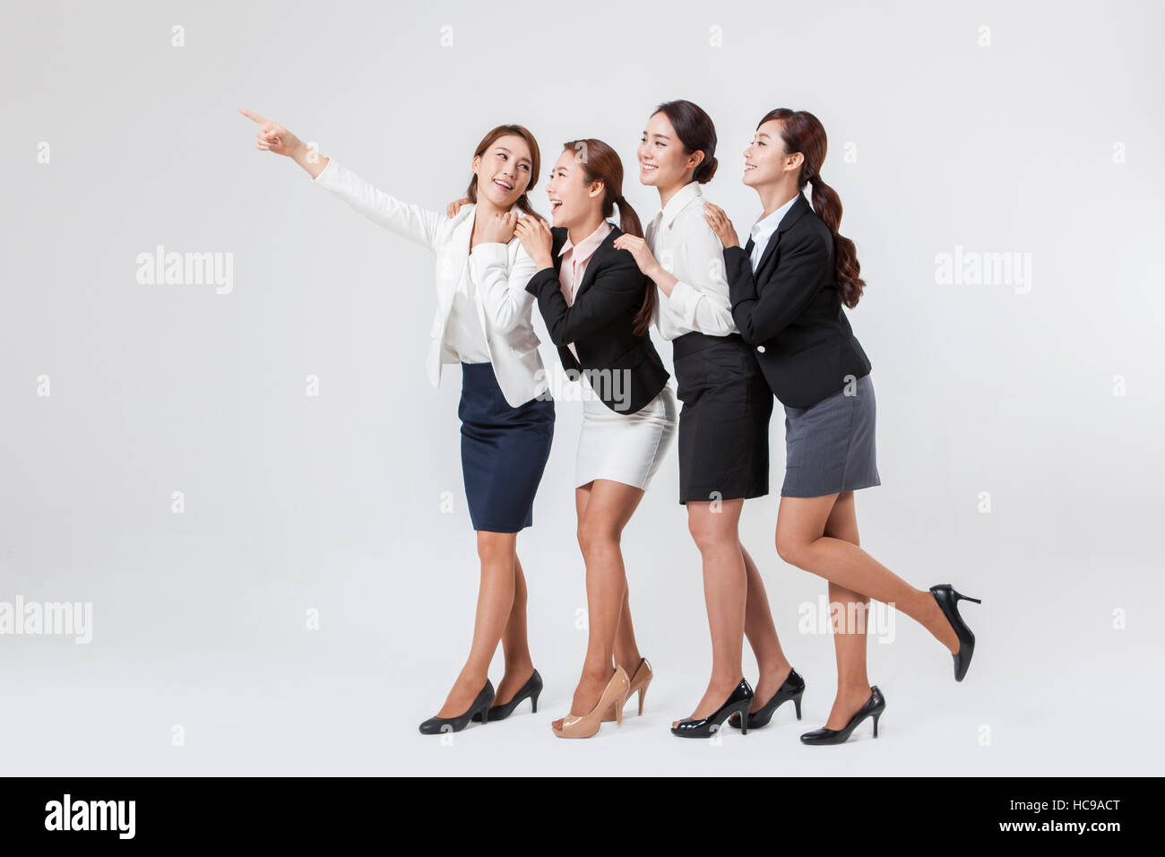 Four young smiling businesswomen standing in a line Stock Photo - Alamy