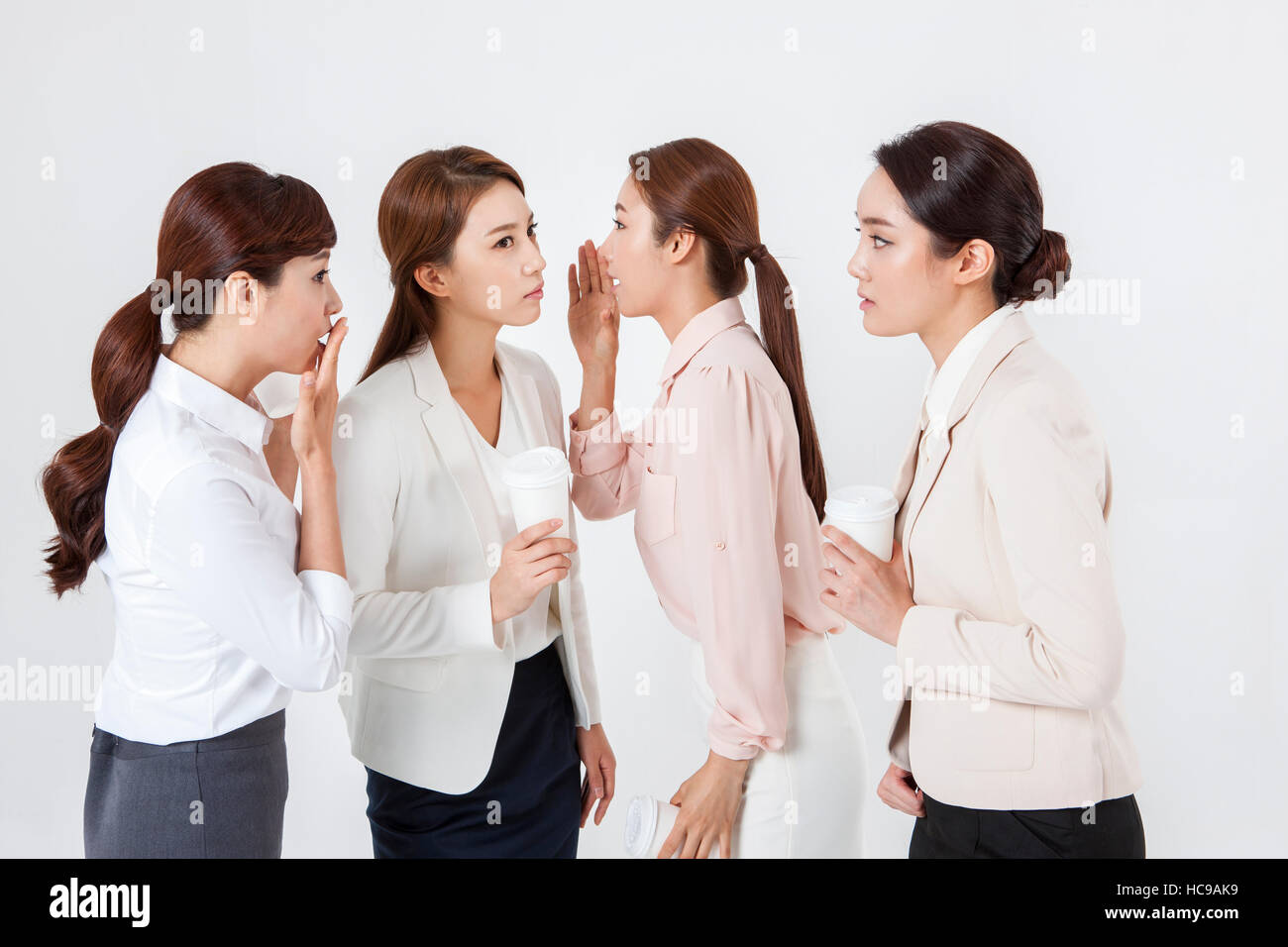 Four young businesswomen talking in whisper Stock Photo - Alamy