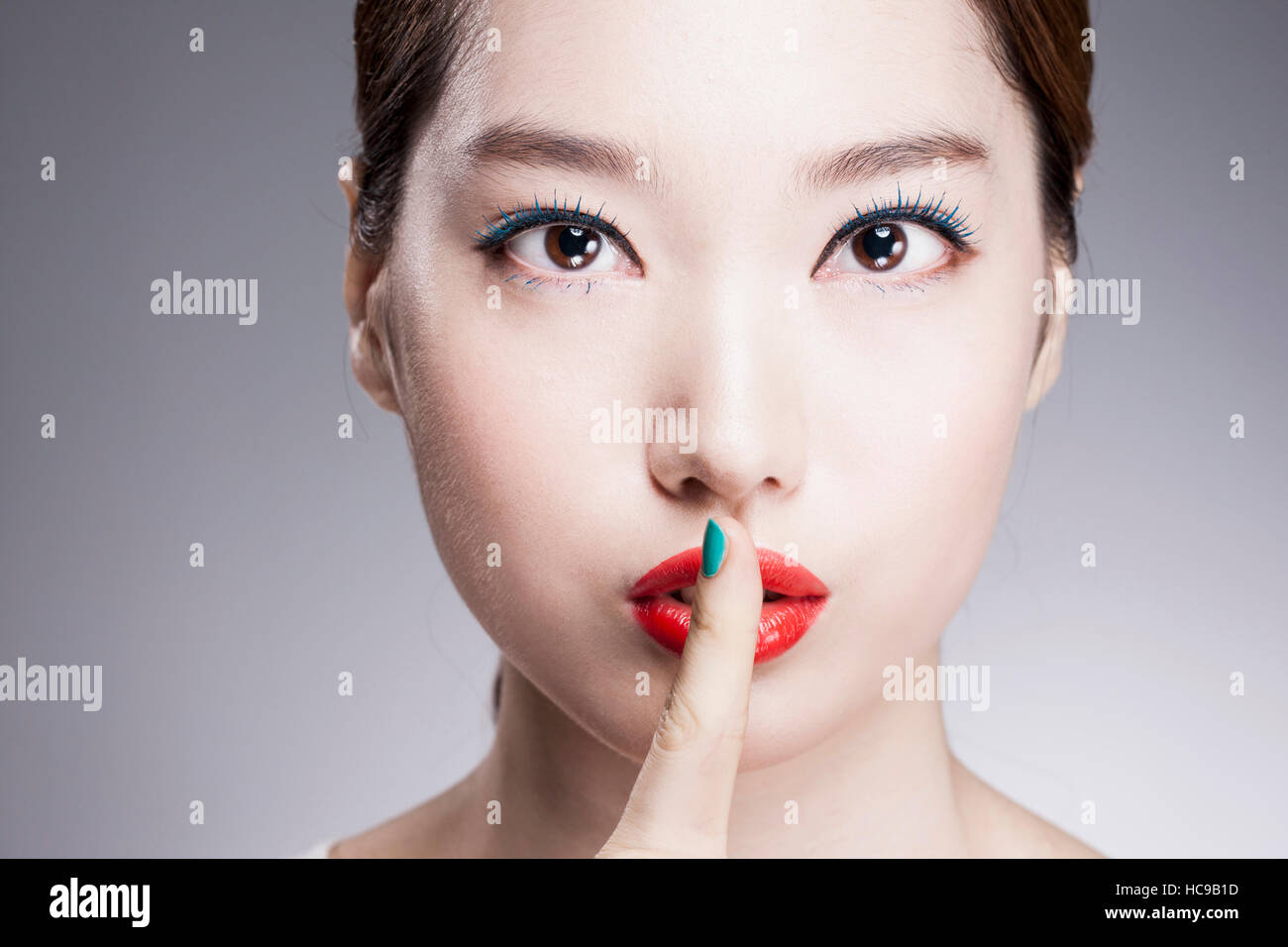 Portrait of young Korean woman putting her finger on her lip Stock ...