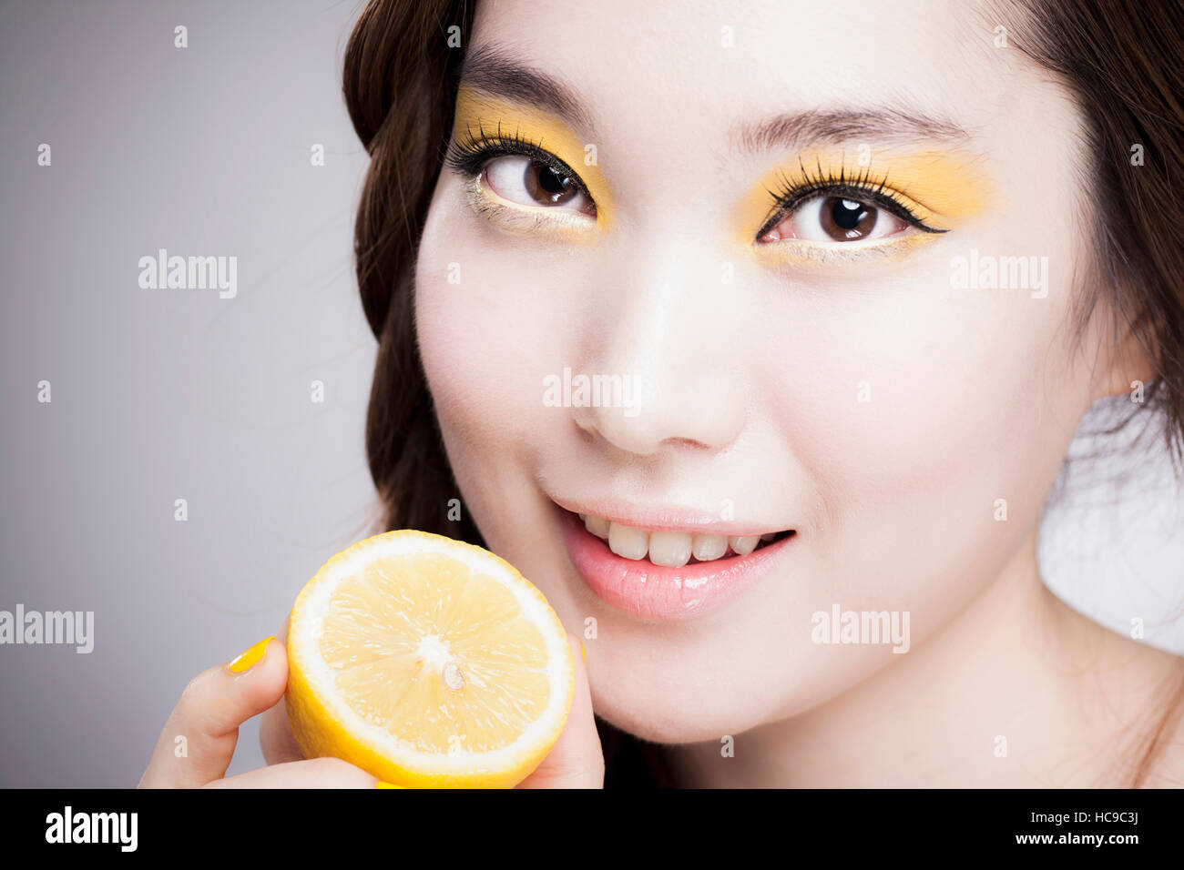 Face of young smiling Korean woman in yellow eye shadow posing with ...
