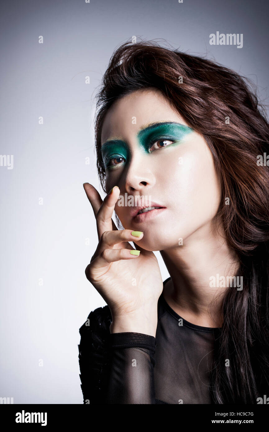 Portrait of young Korean woman in green eye shadow and black clothes ...