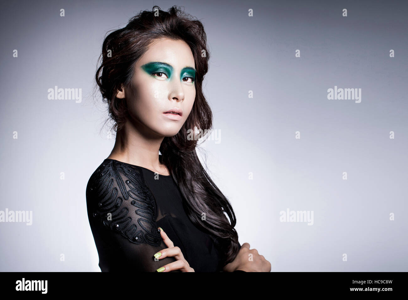 Side view portrait of young Korean woman in black clothes and green eye ...