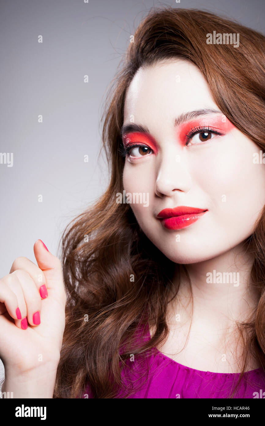 Portrait of young smiling Korean woman in red eye shadow and red lips ...