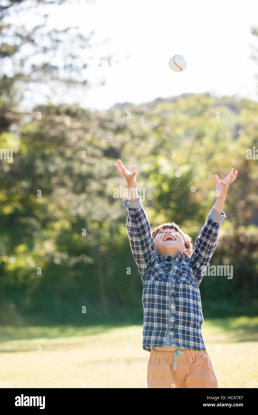 Five-year-old Korean boy reaching for a baseball on grassland Stock ...