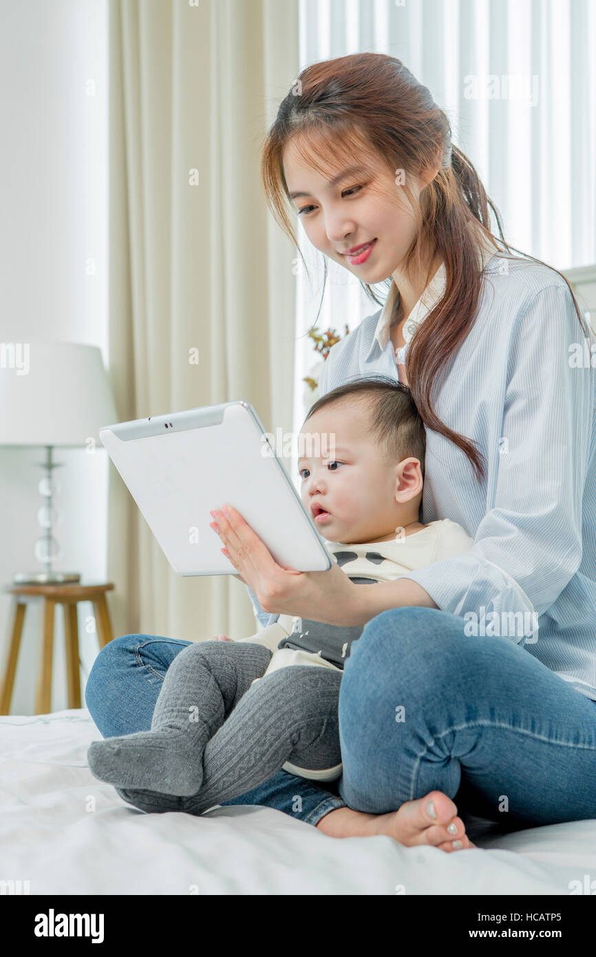 Smiling mother sharing a tablet with her baby Stock Photo - Alamy