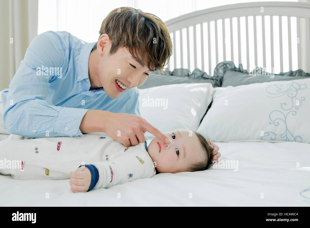 Portrait of loving father taking care of his baby on bed Stock Photo ...